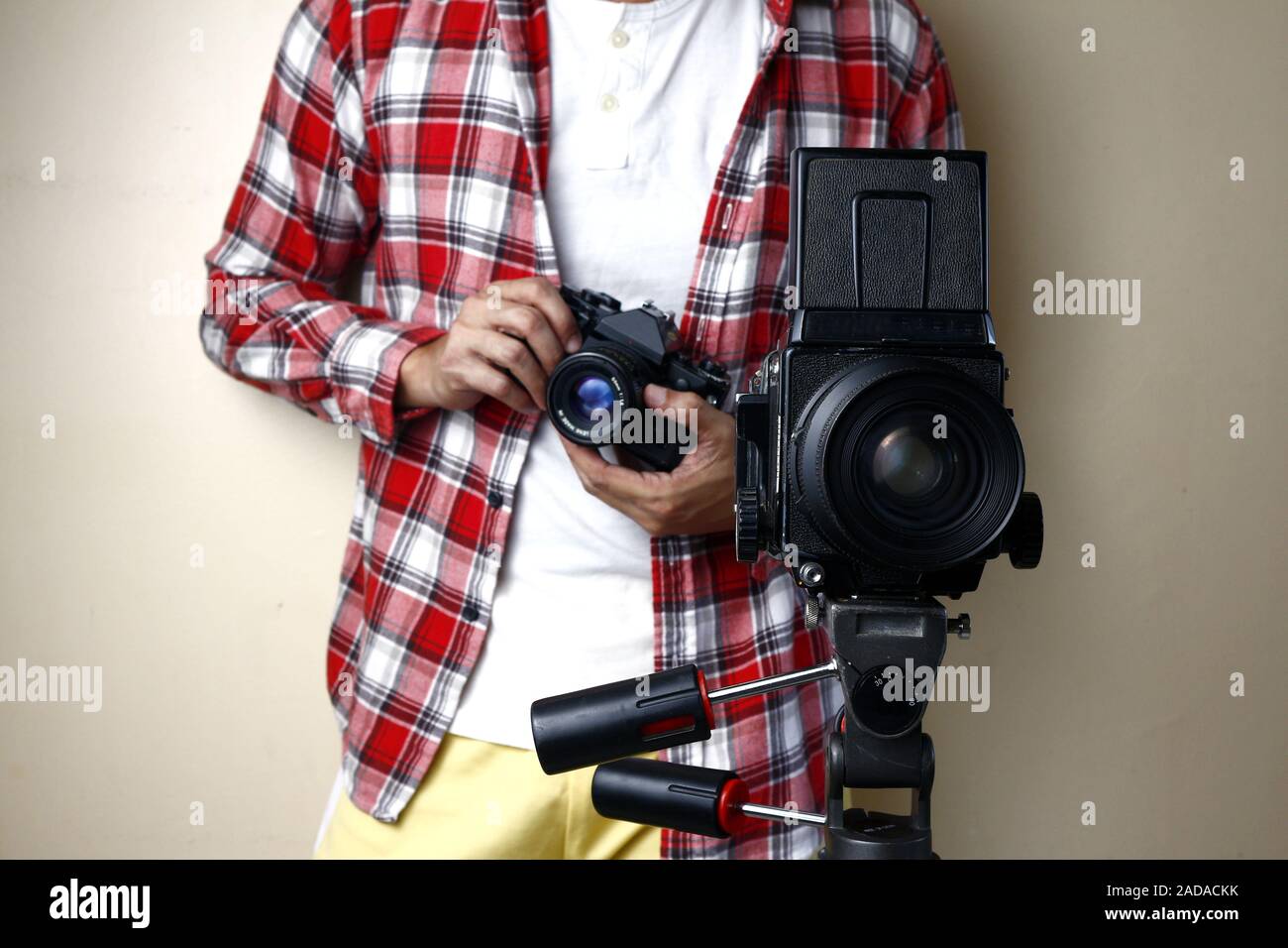 Photo of a man holding a 35mm film camera and standing behind a medium ...