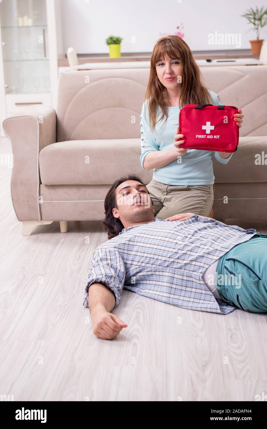 Young couple in first aid concept at home Stock Photo - Alamy