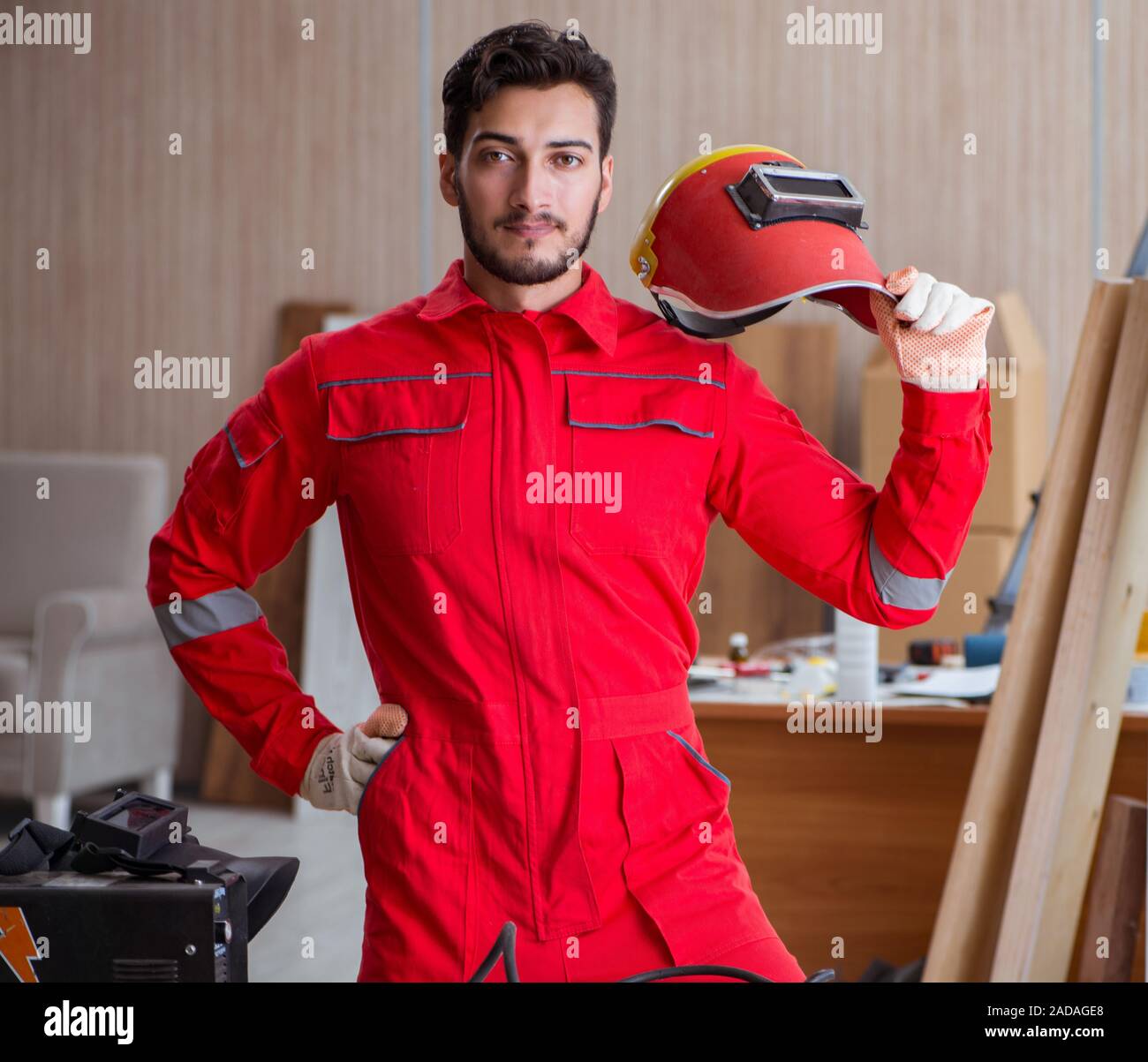 Young repairman with a welding gun electrode and a helmet weldin Stock ...