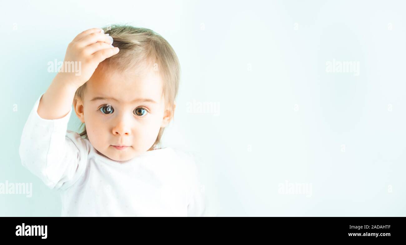 Baby girl with big eyes against the wall. Looking into the camera Stock ...