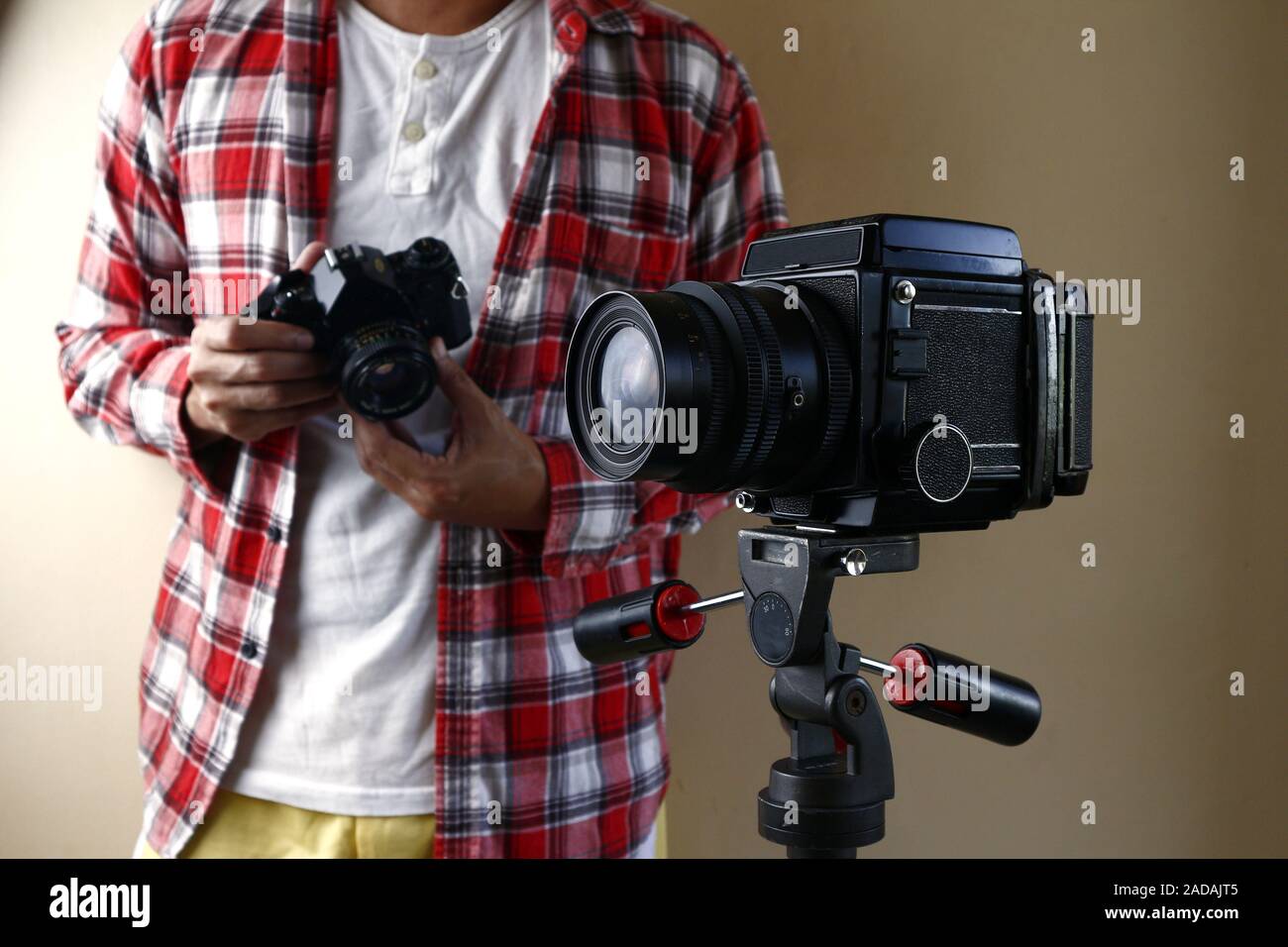 Photo of a man holding a 35mm film camera and standing behind a medium ...