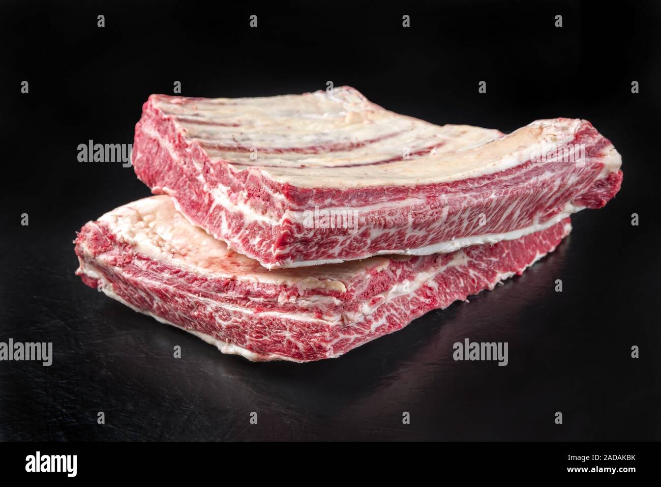 Raw wagyu short loin ribs as closeup on black background with copy ...