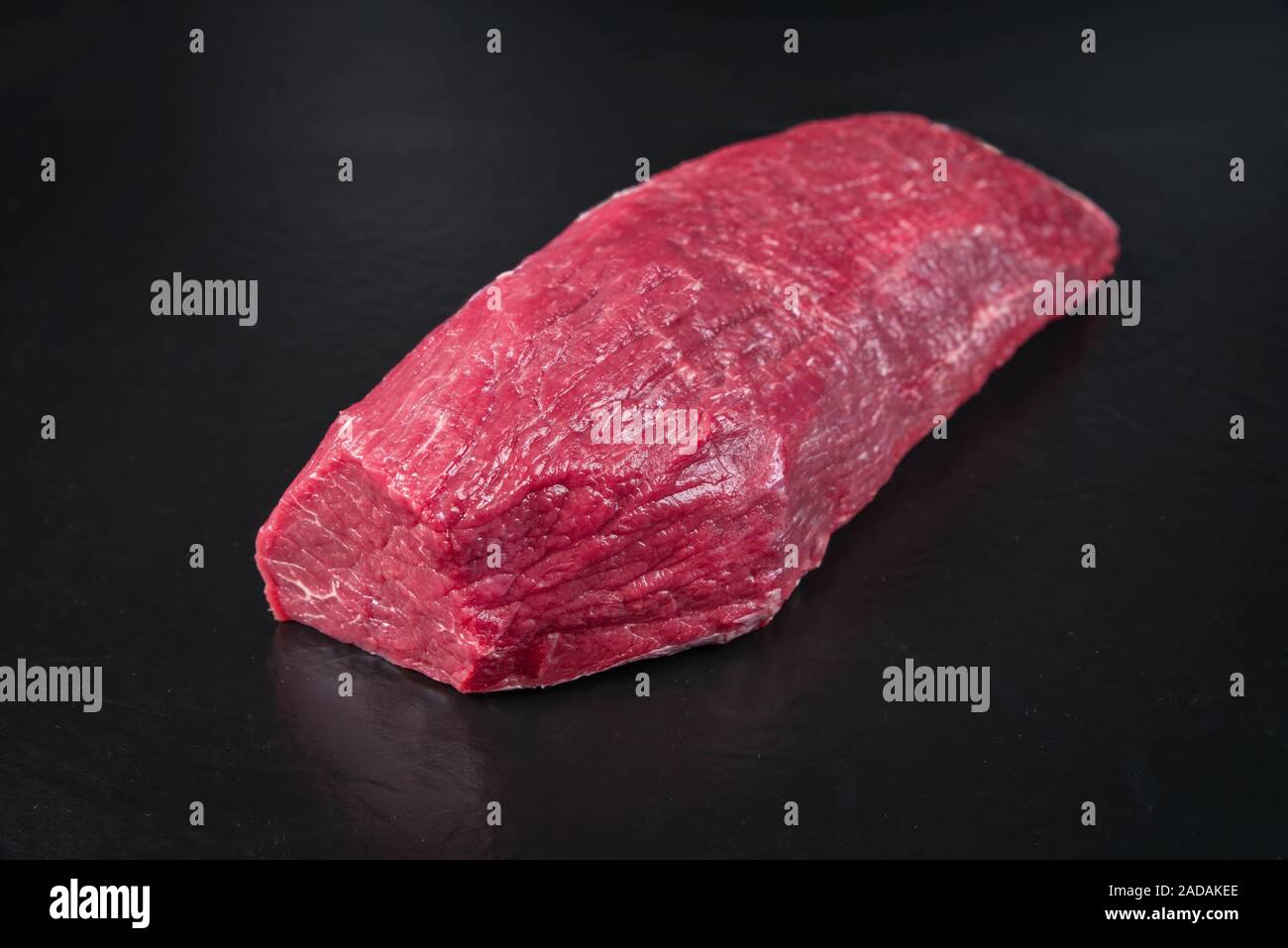 Raw dry aged wagyu beef rump fillet steak piece as closeup on black ...