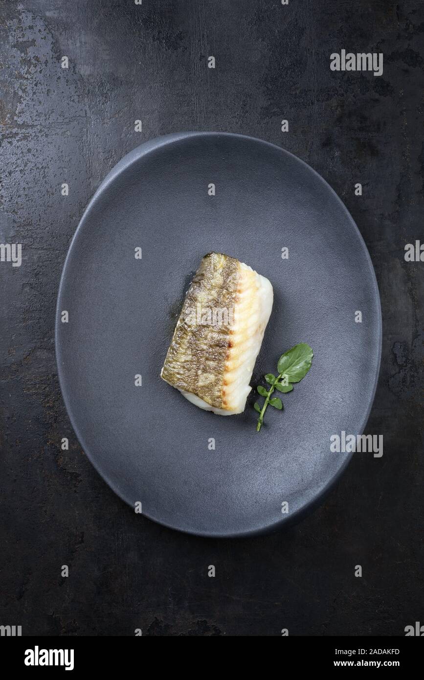 Fried Japanese skrei cod fish filet with wasabi lettuce as top view on ...