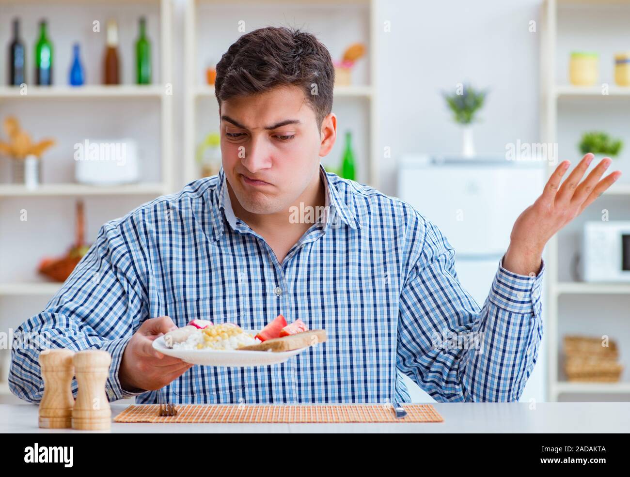 Young husband eating tasteless food at home for lunch Stock Photo - Alamy