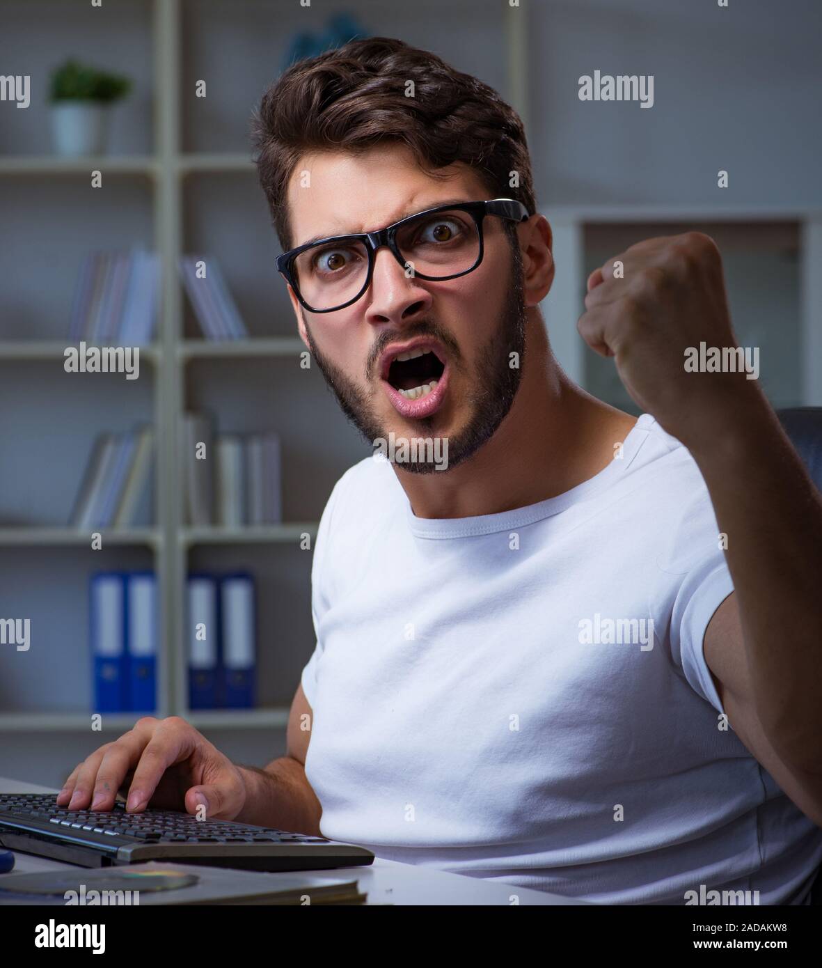 Young man staying late in office to do overtime work Stock Photo - Alamy