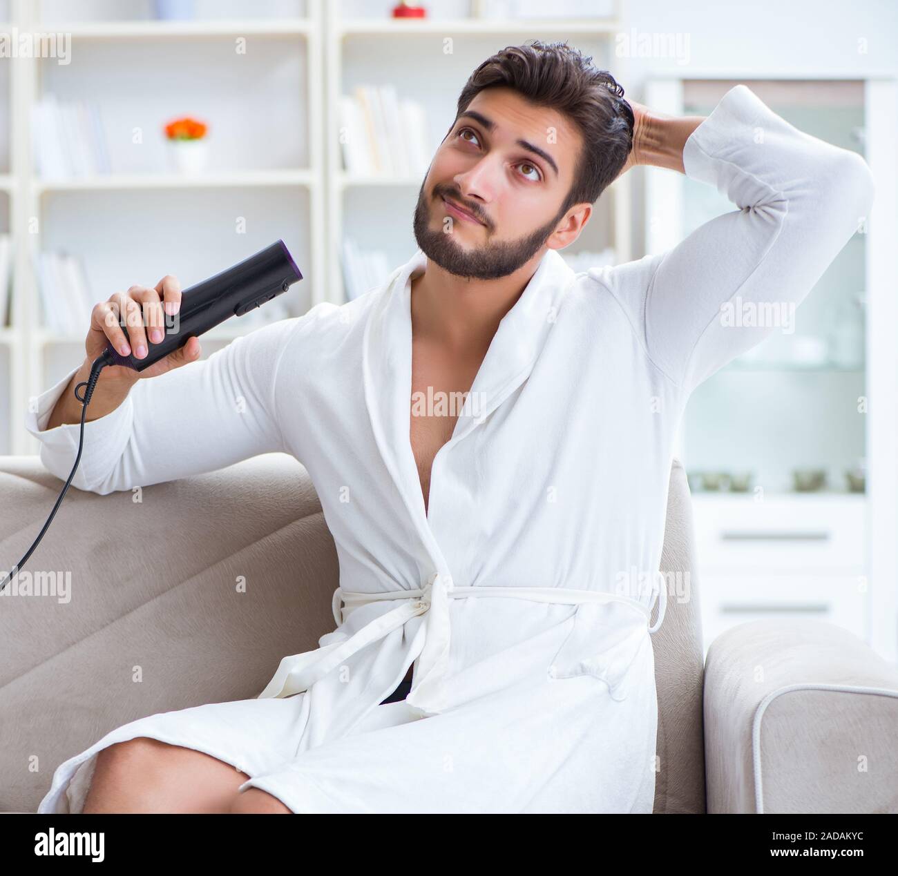 Young man drying hair at home with a hair dryer blower Stock Photo - Alamy