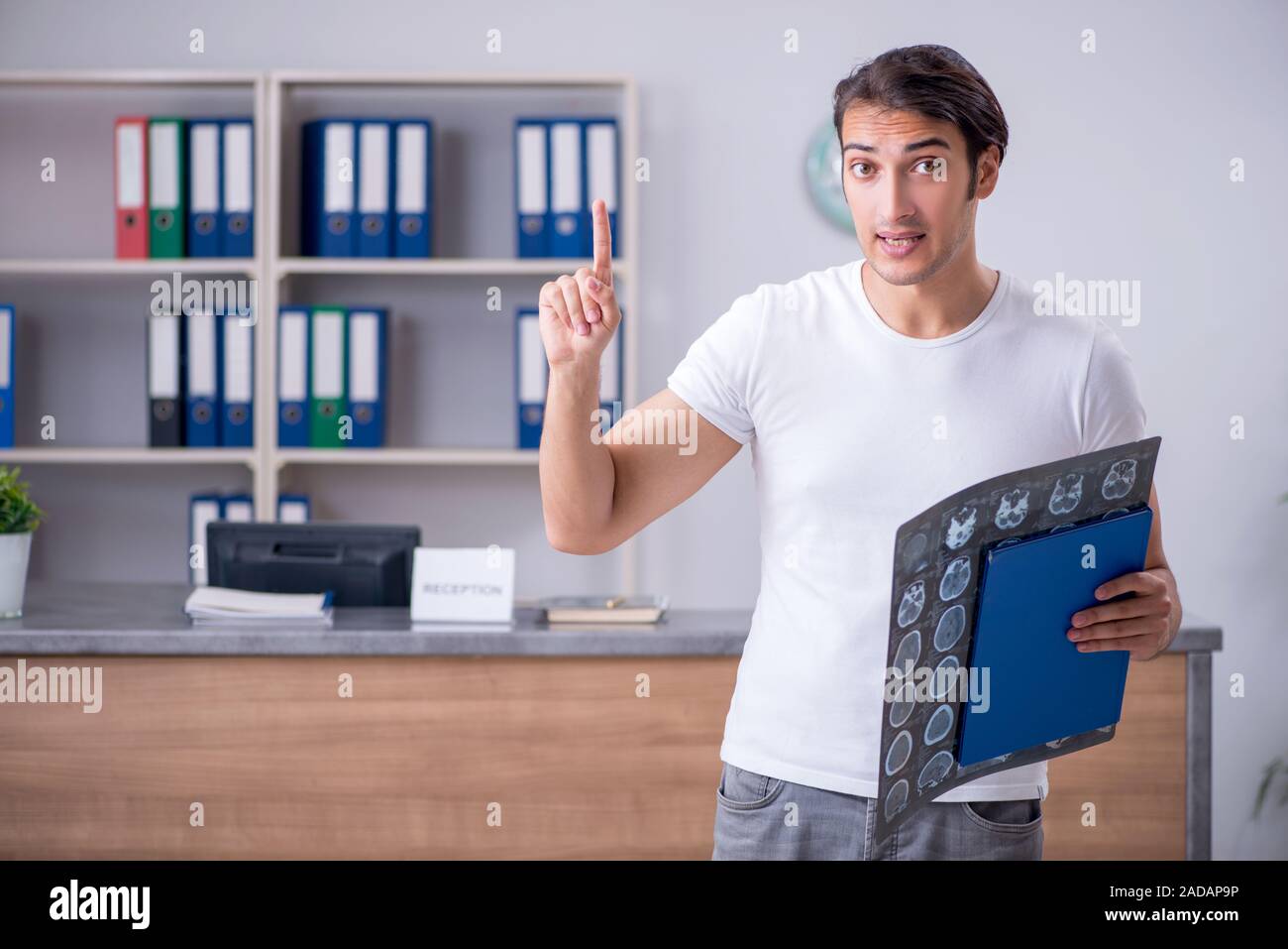 Young man at hospital reception desk Stock Photo - Alamy