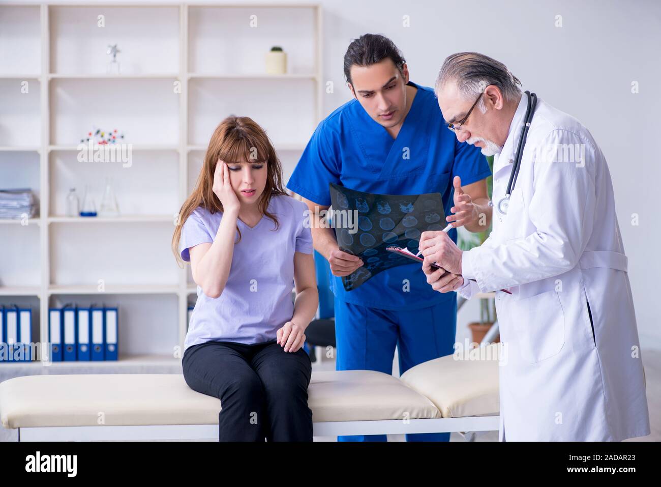 Two doctors examining young woman Stock Photo - Alamy