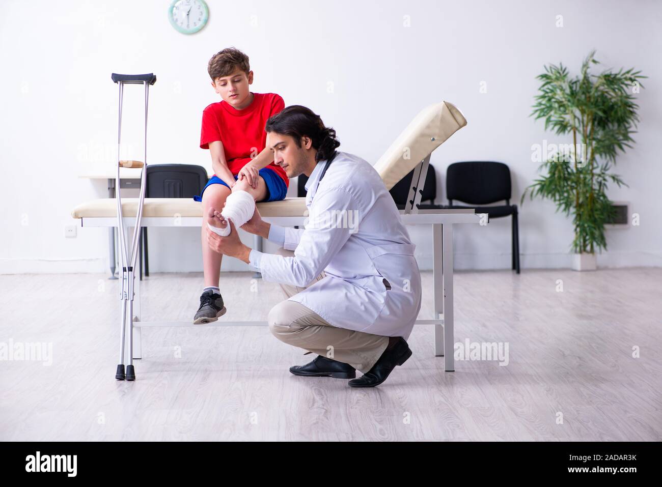 Leg injured boy visiting young doctor traumatologist Stock Photo - Alamy