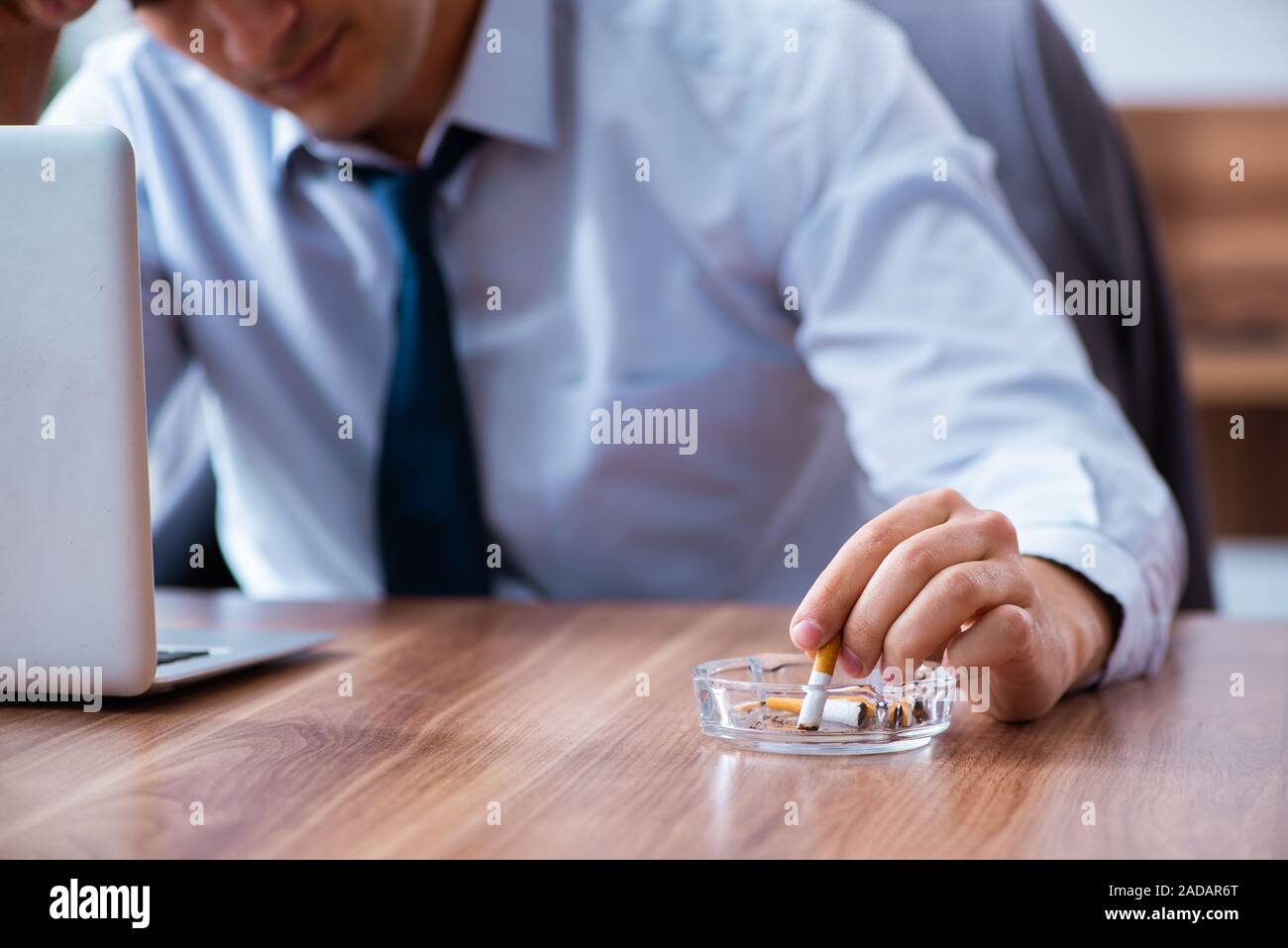 Male employee smoking cigarettes at workplace Stock Photo - Alamy