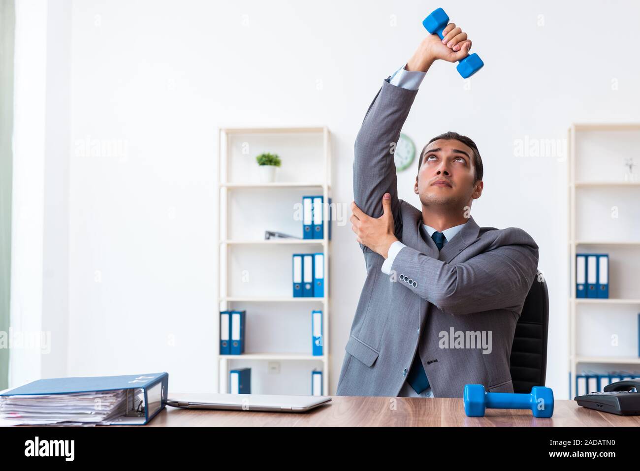 Young handsome employee doing sport exercises at workplace Stock Photo ...