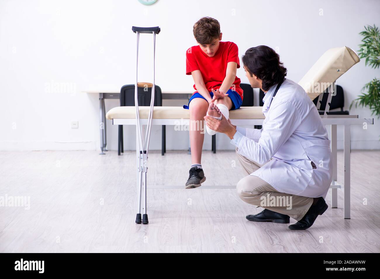 Leg injured boy visiting young doctor traumatologist Stock Photo - Alamy