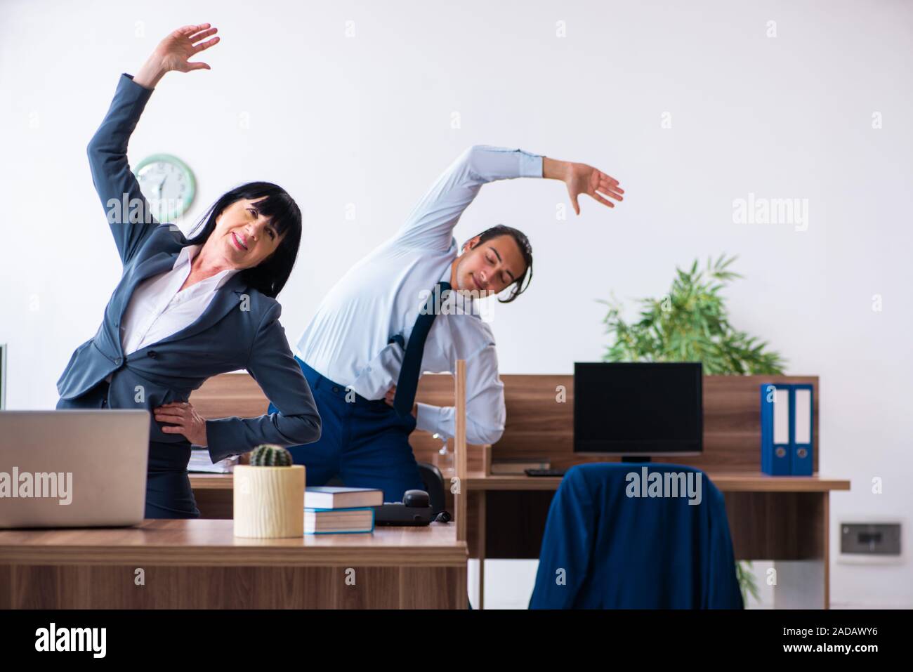 Two employees doing sport exercises in the office Stock Photo - Alamy