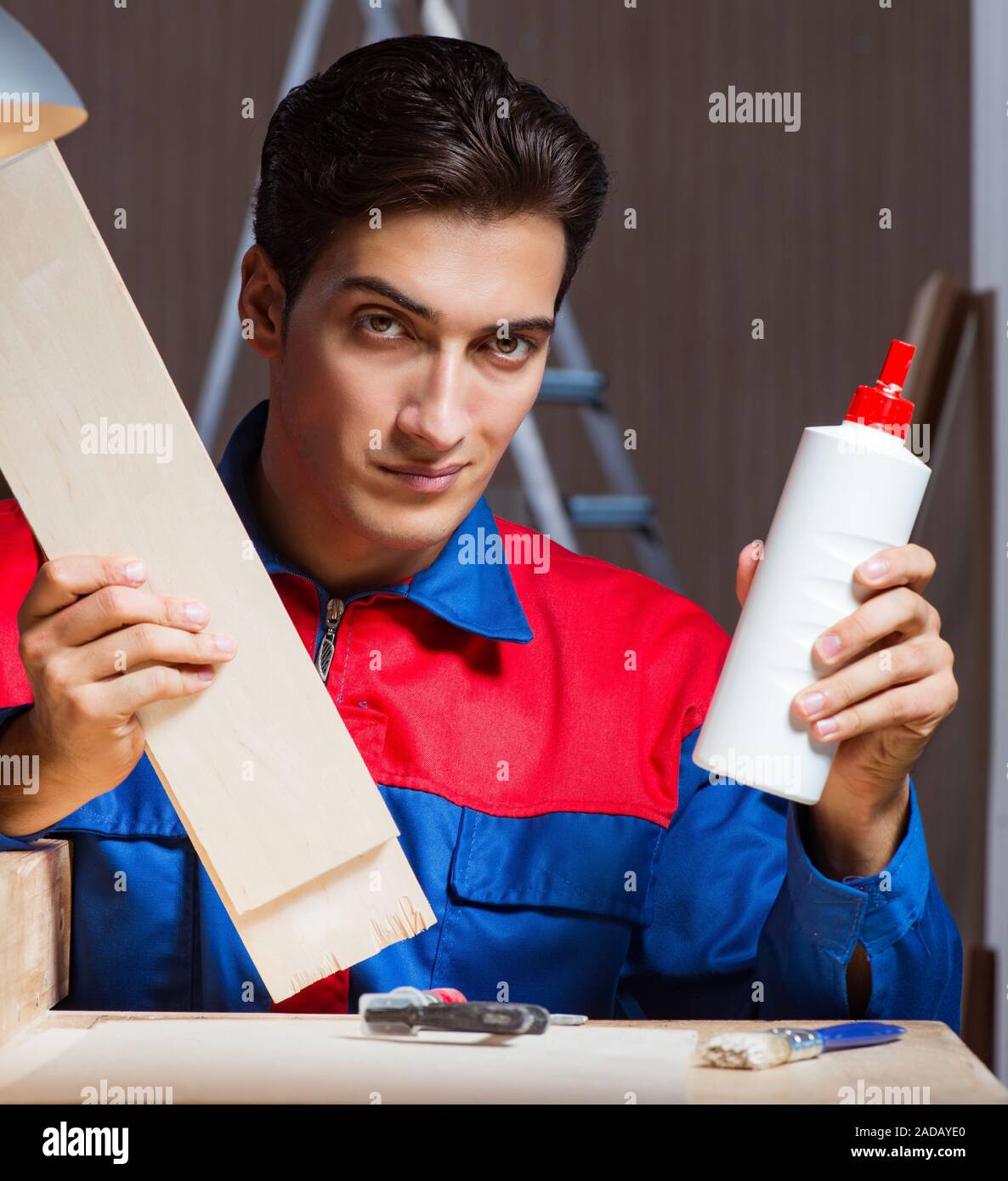 Young man gluing wood pieces together in DIY concept Stock Photo - Alamy