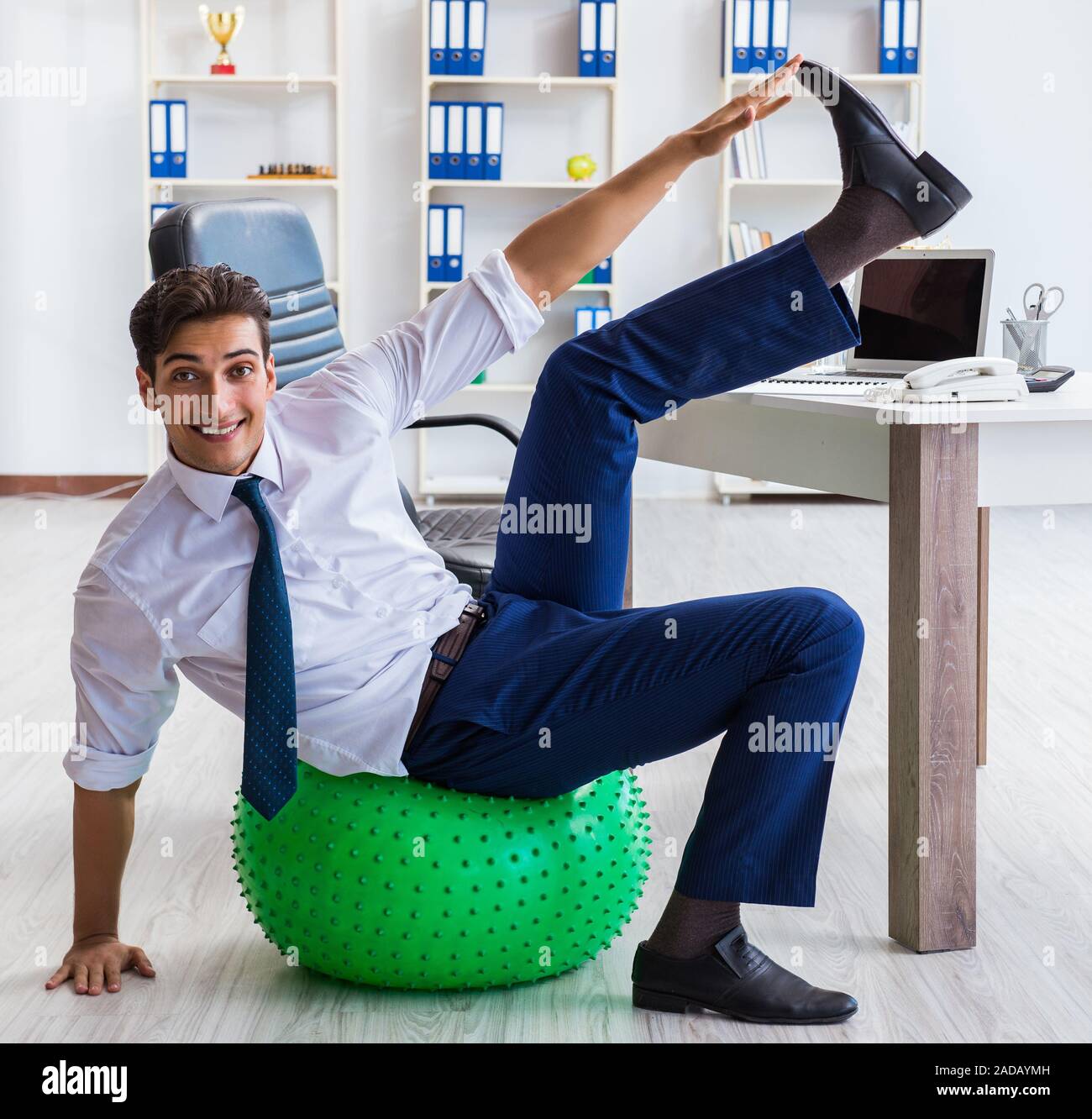 Young Businessman doing sports stretching at workplace Stock Photo - Alamy