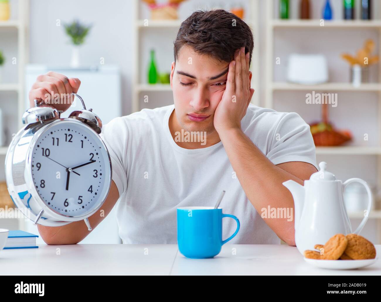 Man with alarm clock falling asleep at breakfast Stock Photo - Alamy