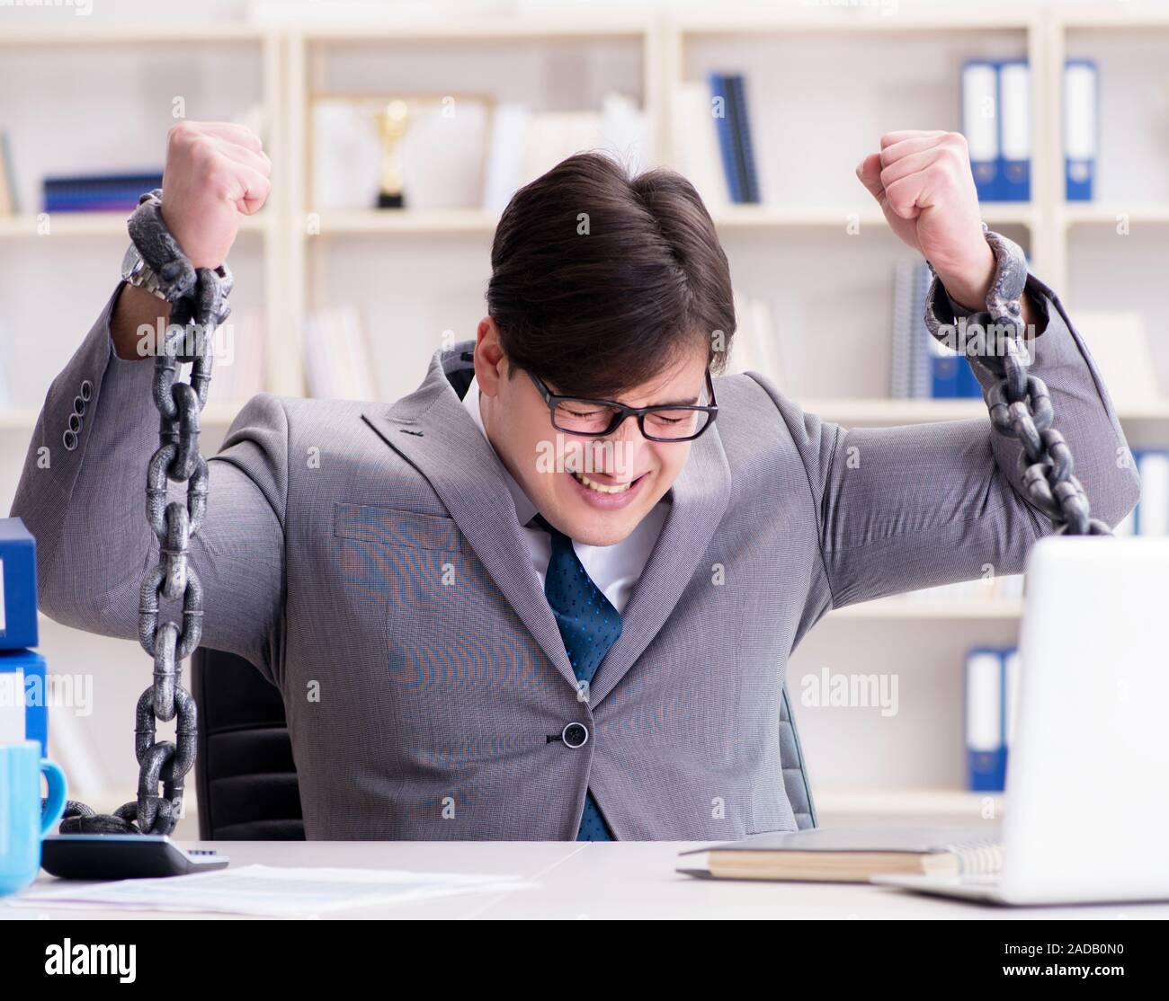Businessman tied with chains to his work Stock Photo - Alamy