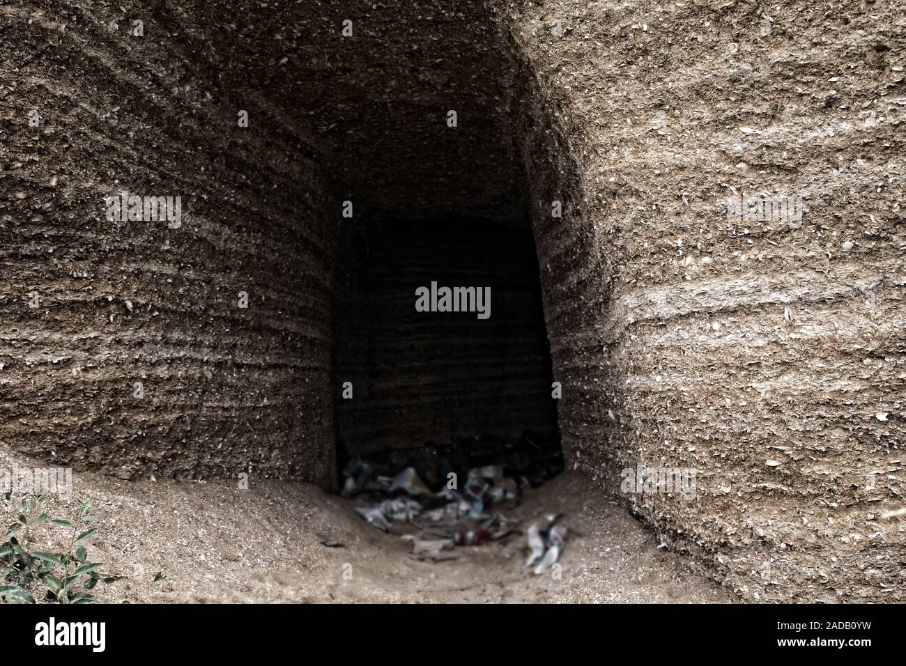 Littered with debris entrance to cave Stock Photo - Alamy
