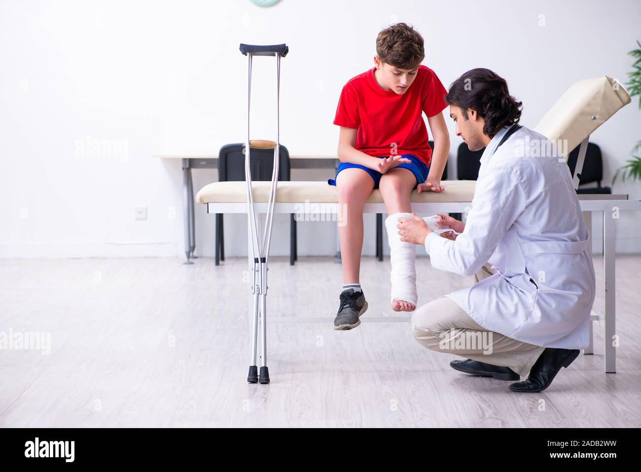 Leg injured boy visiting young doctor traumatologist Stock Photo - Alamy