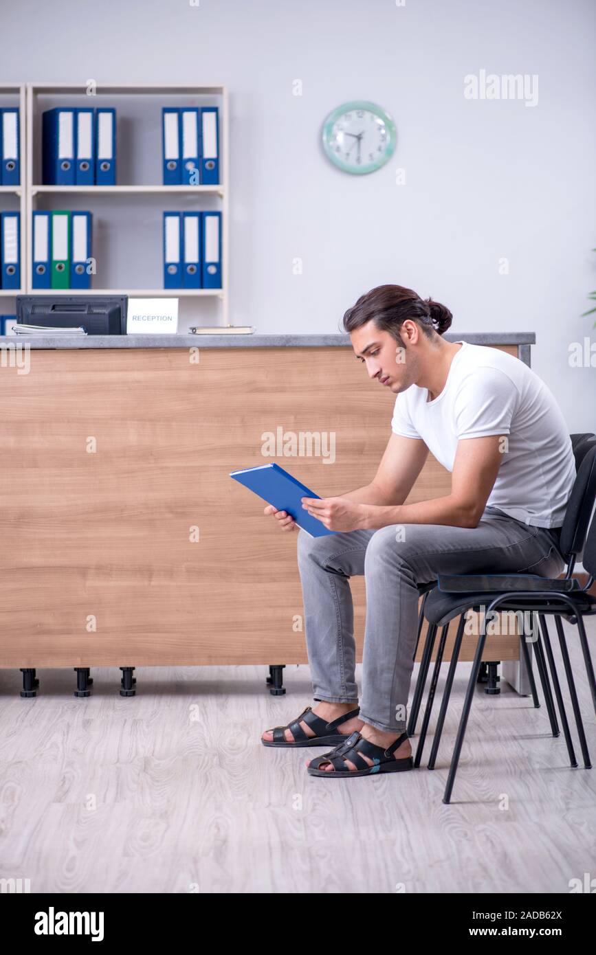 Young man at hospital reception desk Stock Photo - Alamy