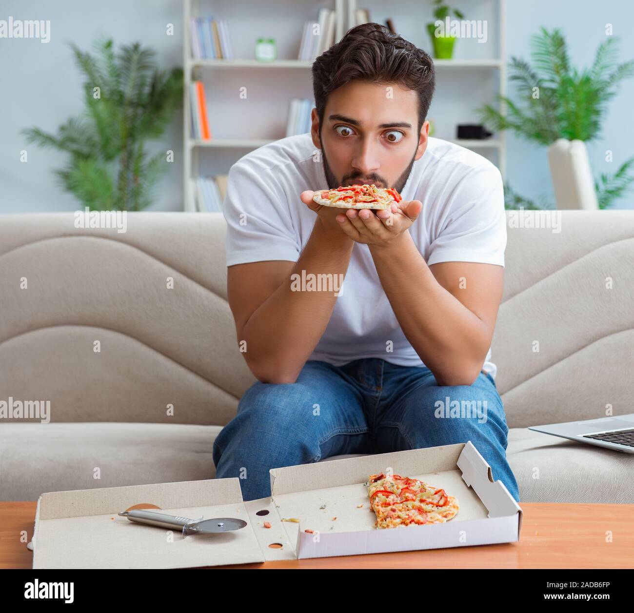 Man eating pizza having a takeaway at home relaxing resting Stock Photo ...