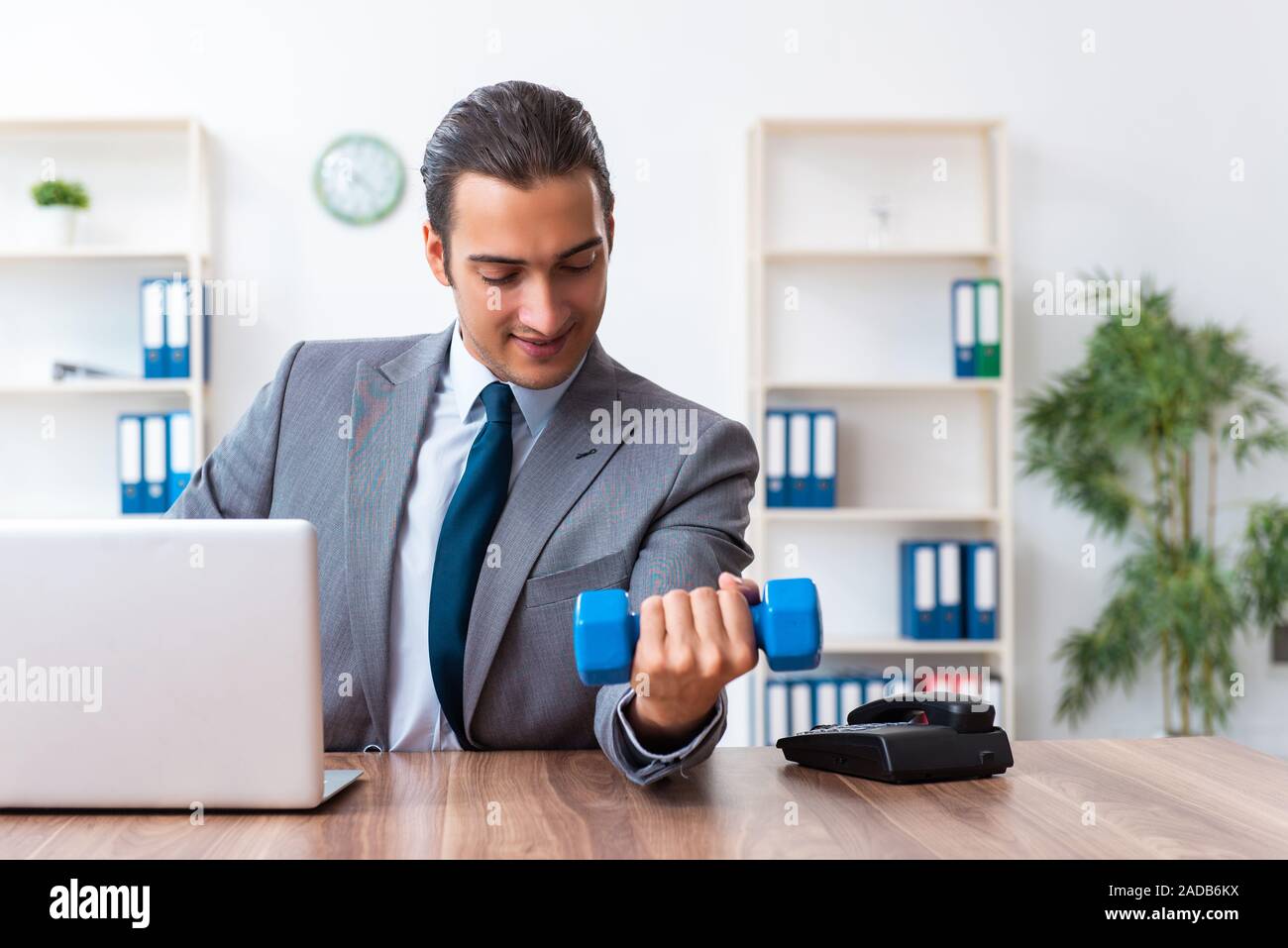 Young handsome employee doing sport exercises at workplace Stock Photo ...