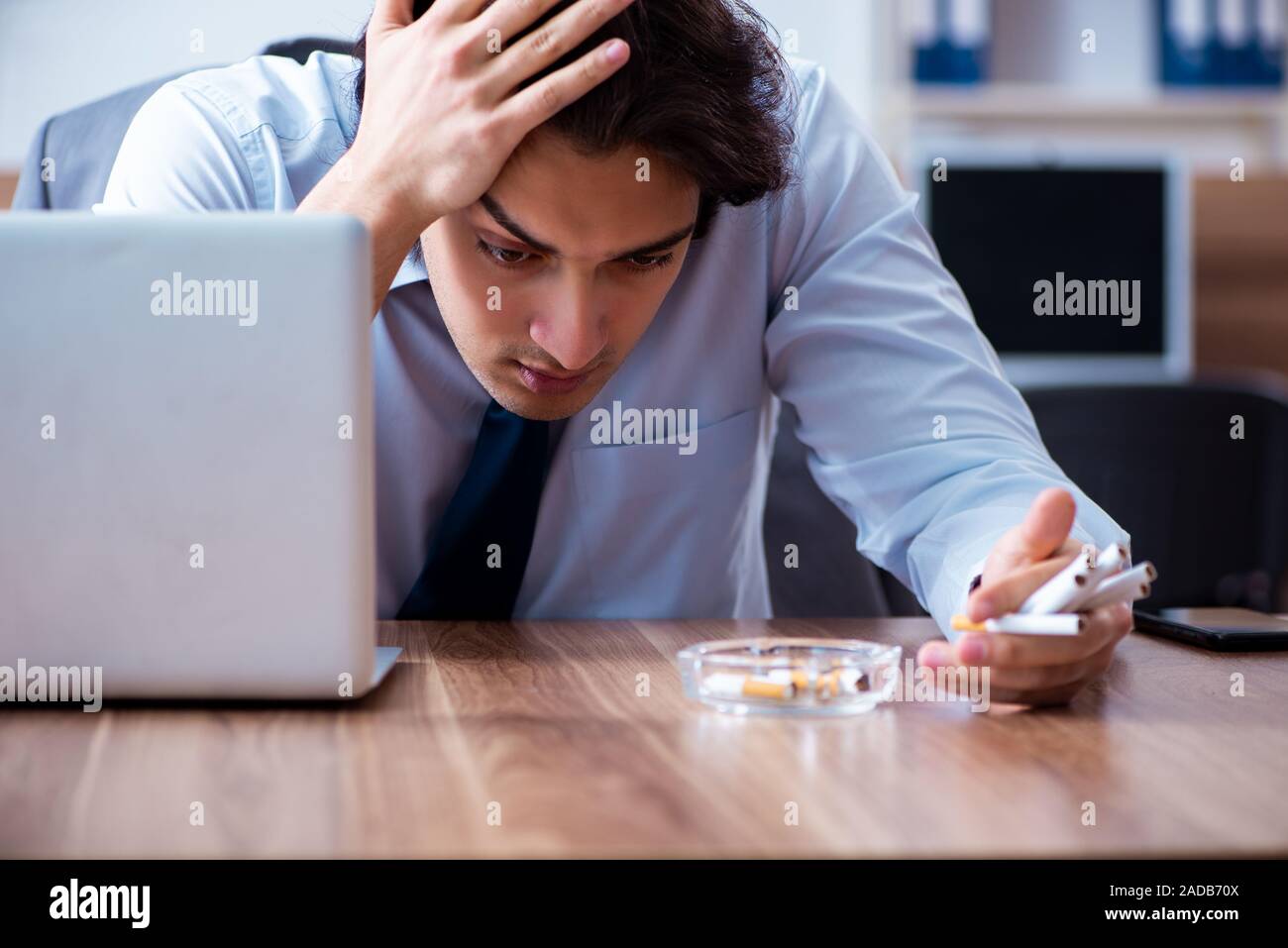Male employee smoking cigarettes at workplace Stock Photo - Alamy