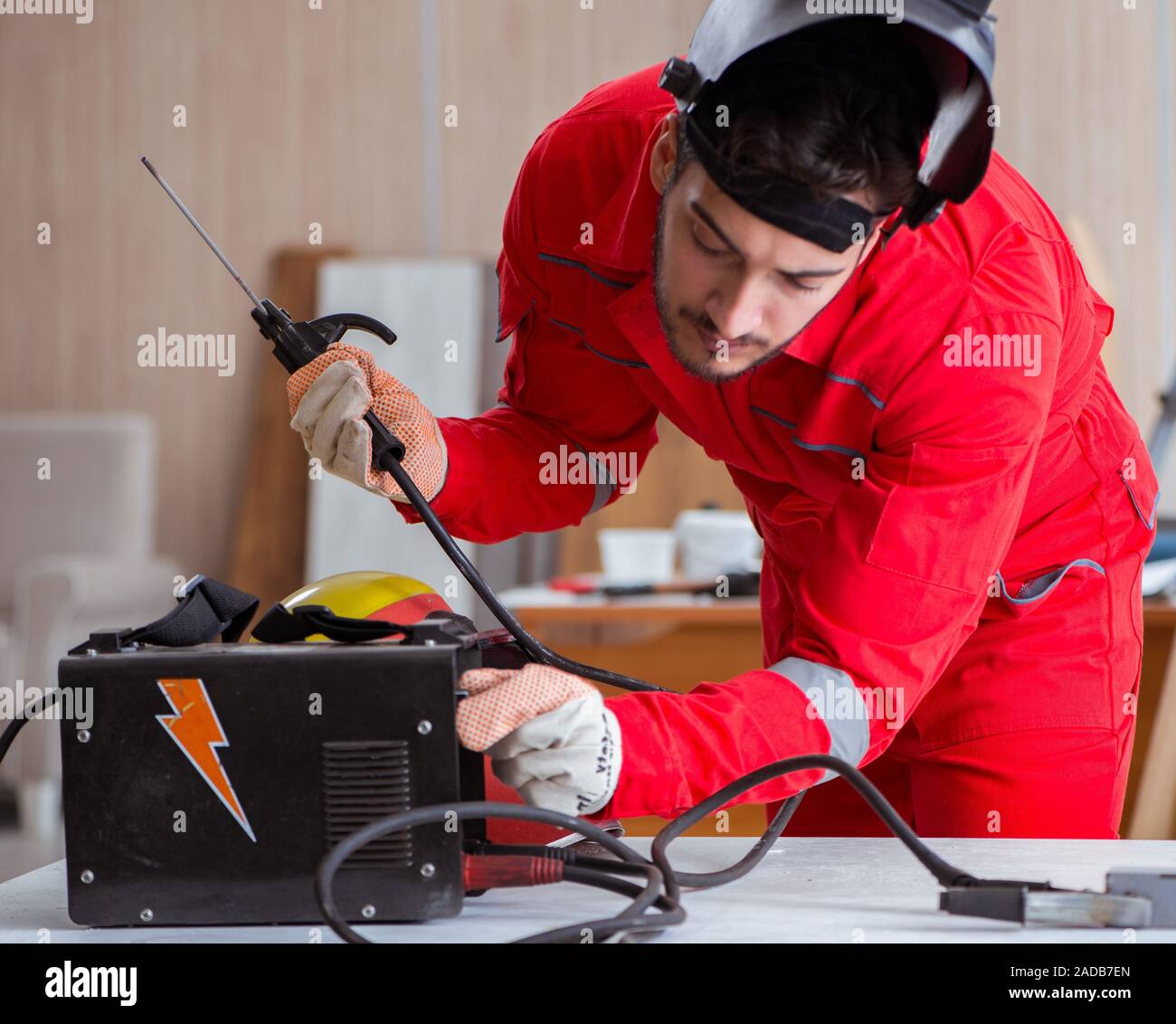 Young repairman with a welding gun electrode and a helmet weldin Stock ...