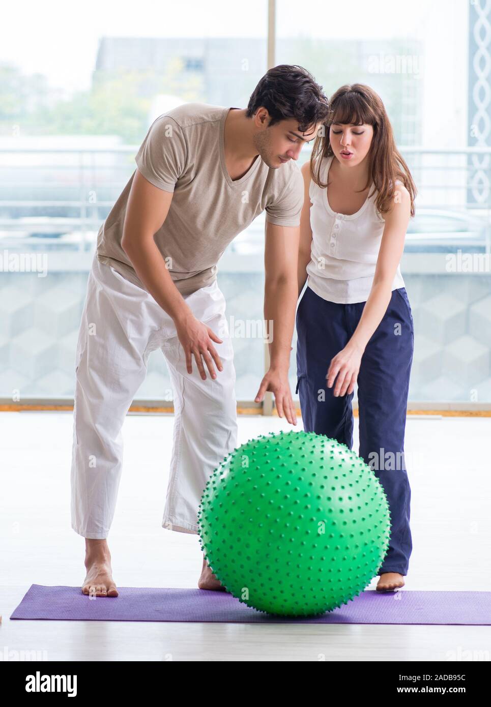 Personal coach helping woman in gym with stability ball Stock Photo - Alamy