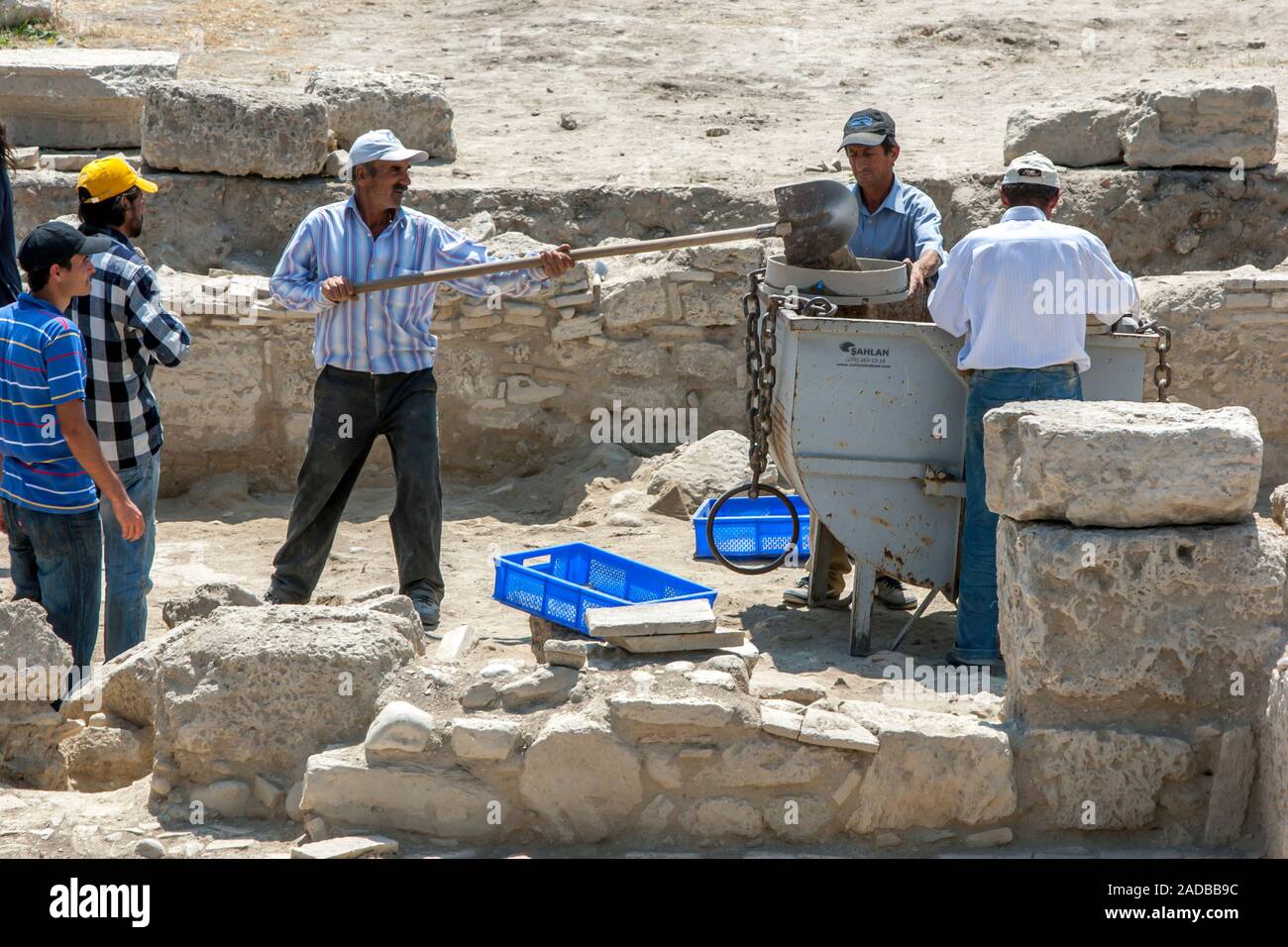 A worker tips a shovel of soil into a sifting tray whilst excavating ...