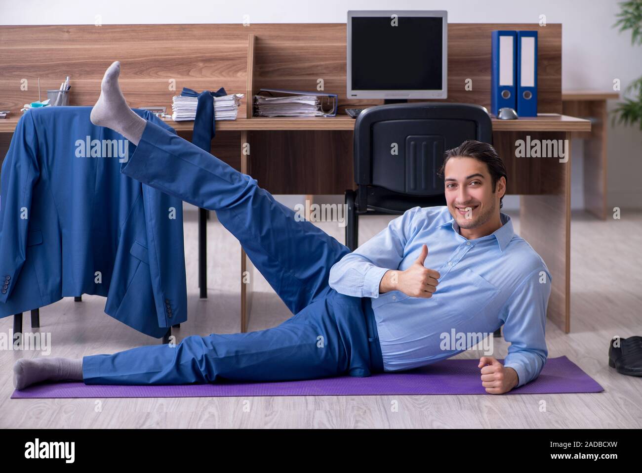 Young handsome Businessman doing exercises at workplace Stock Photo - Alamy