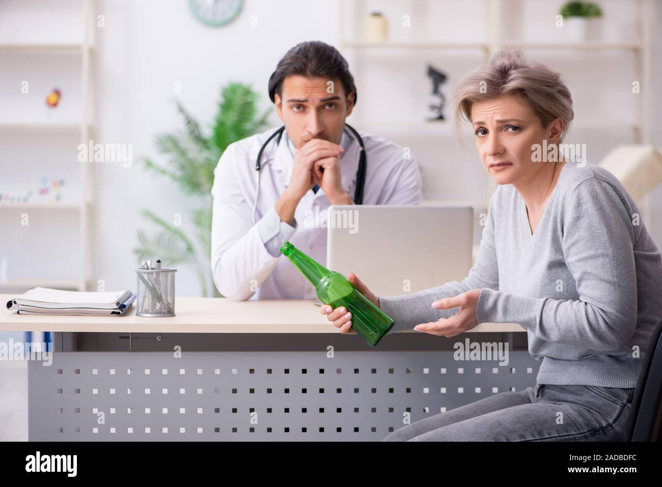 Female alcoholic visiting young male doctor Stock Photo - Alamy