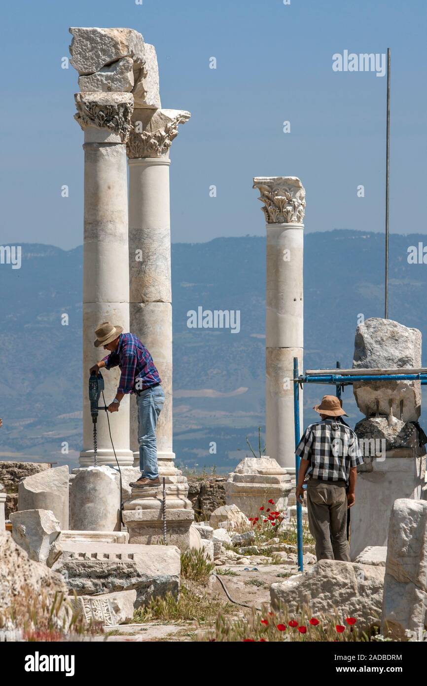 A worker drills a hole through a stone column during reconstructed work ...