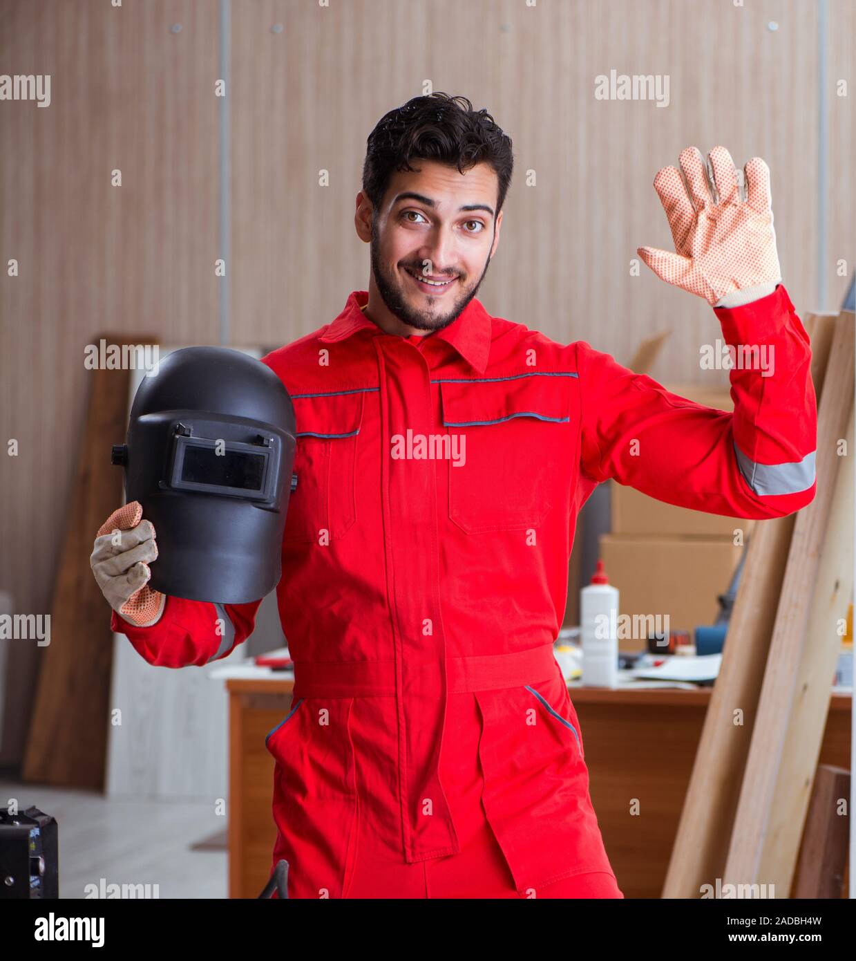 Young repairman with a welding gun electrode and a helmet weldin Stock ...