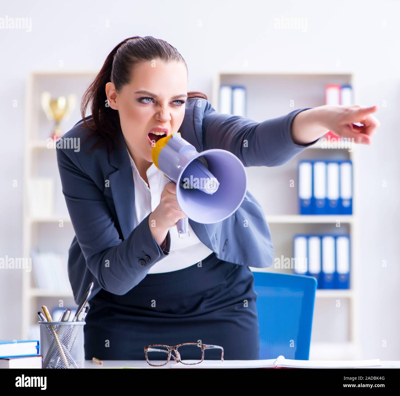 Angry Businesswoman yelling with loudspeaker in office Stock Photo - Alamy