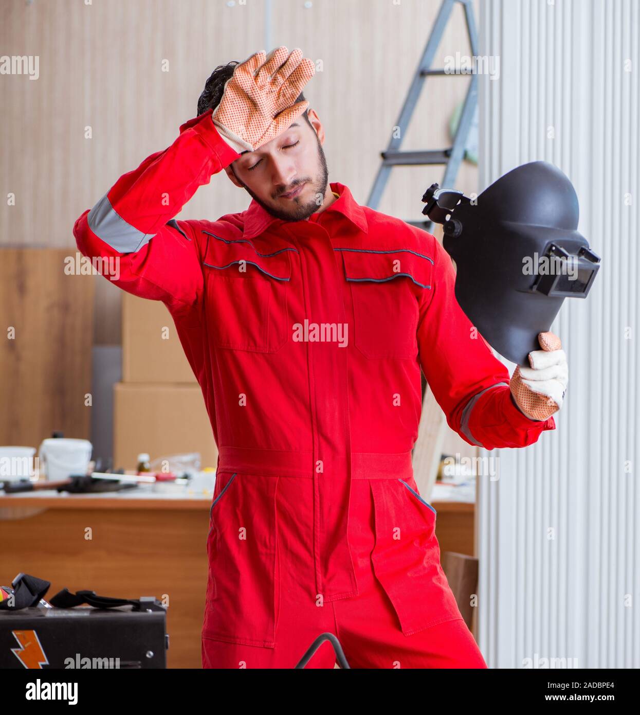 Young repairman with a welding gun electrode and a helmet weldin Stock ...