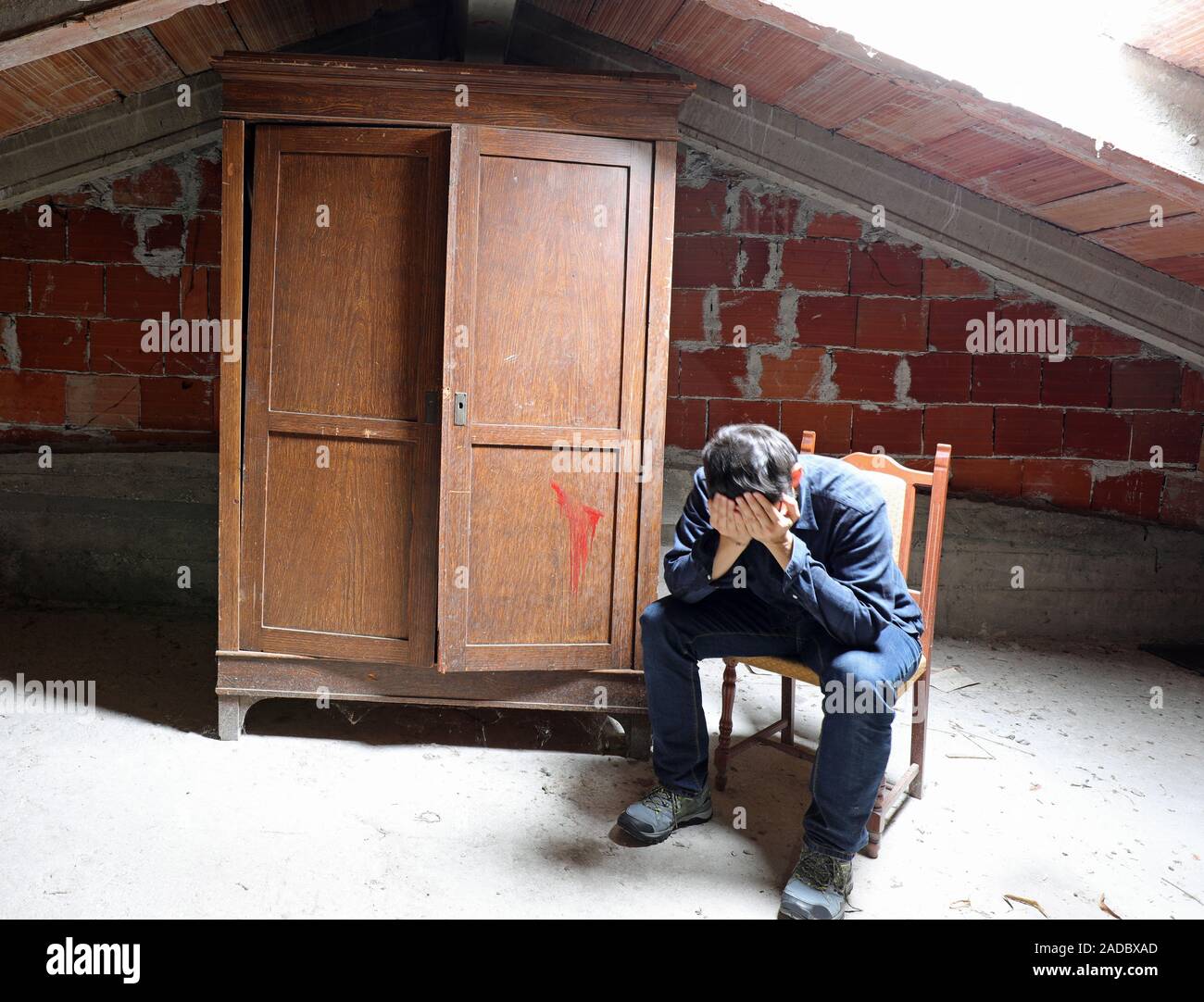 wooden wardrobe and a sad man in the attic of an house Stock Photo - Alamy