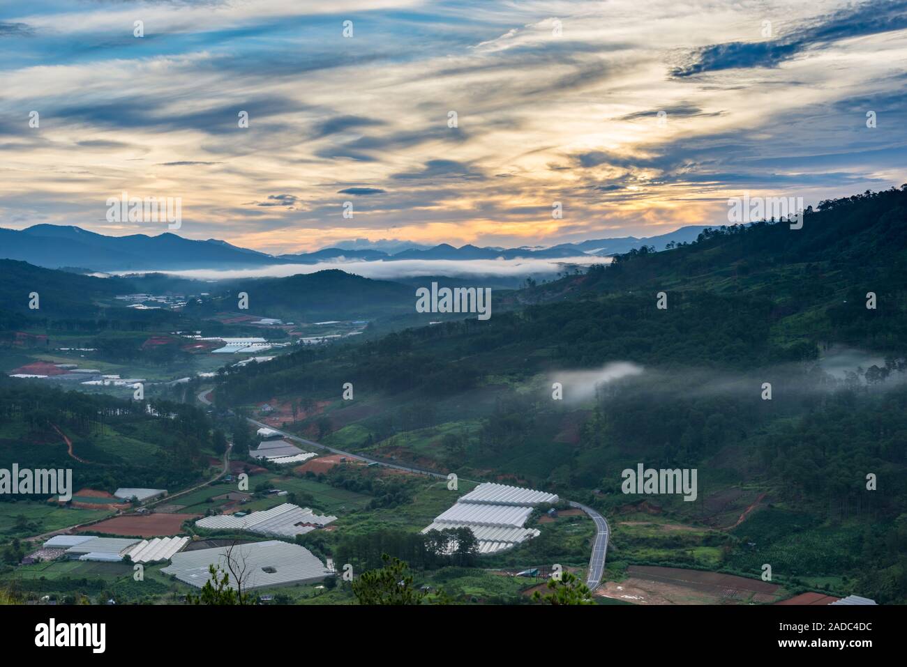 Orange overcast sky at dusk and misty valley scenery Stock Photo - Alamy
