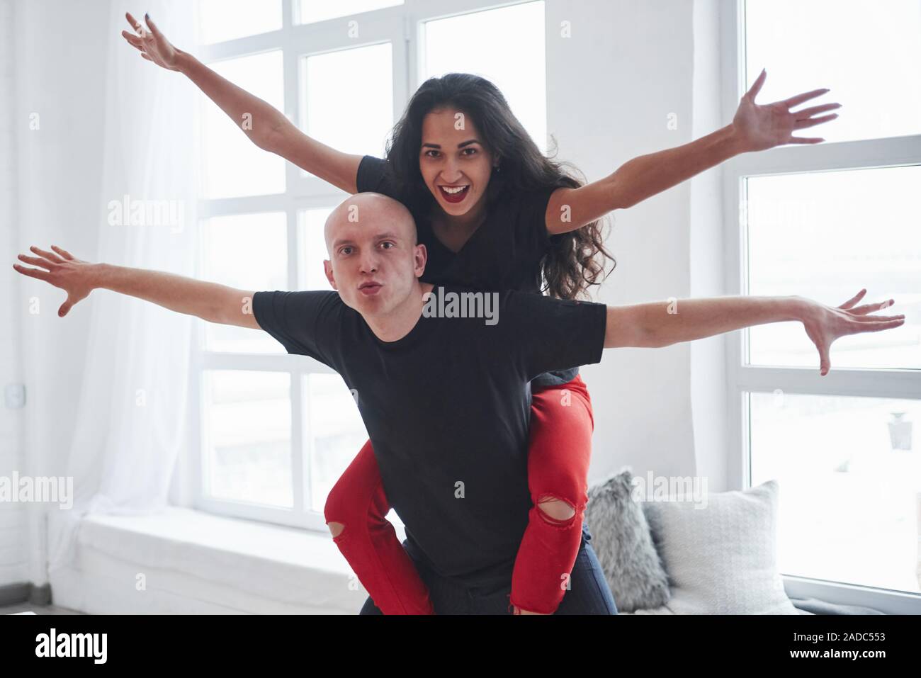 Playful couple in black and red clothes having fun in the white room in ...