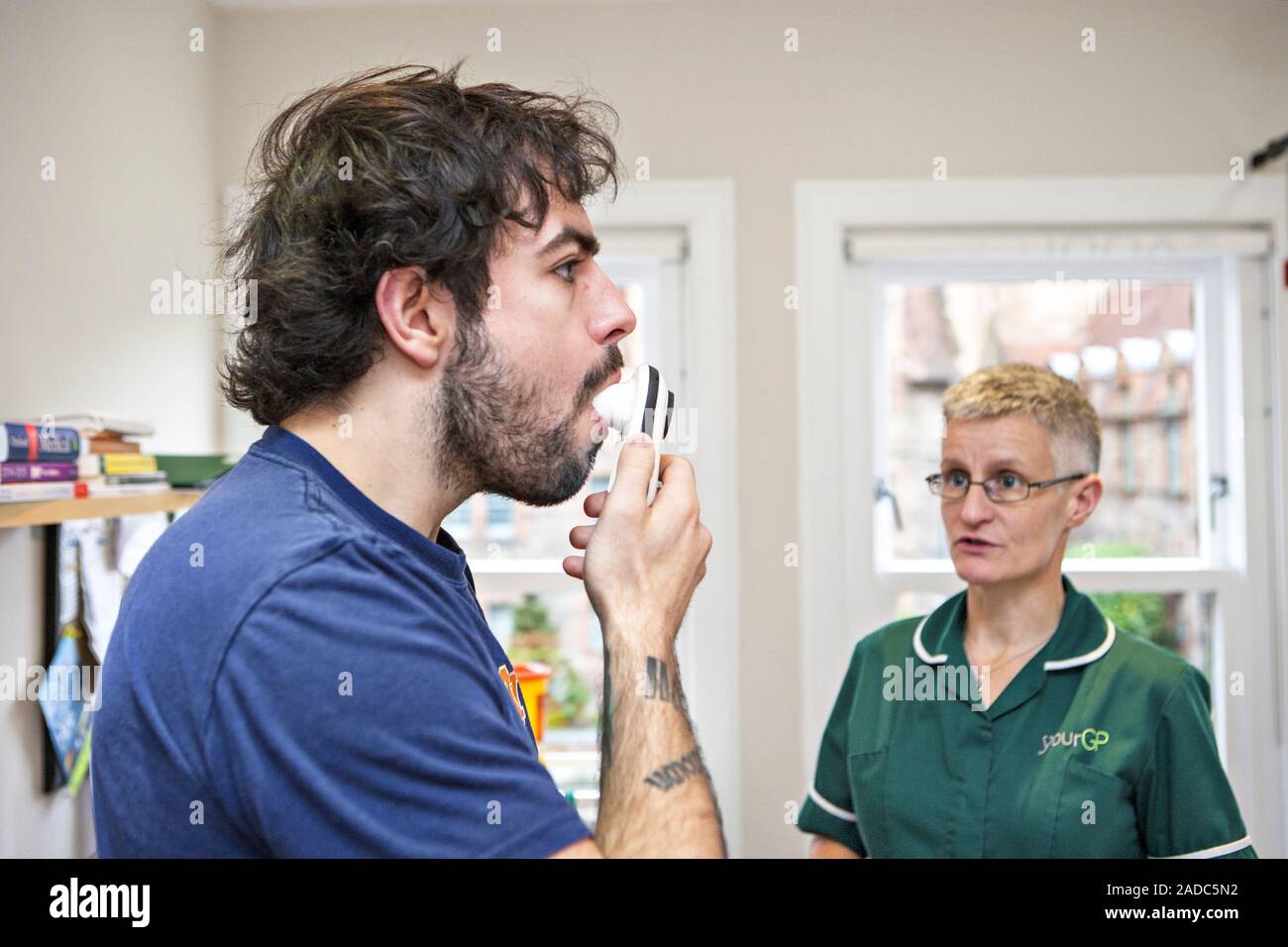 Lung function testing. Patient exhaling hard into a small handheld ...