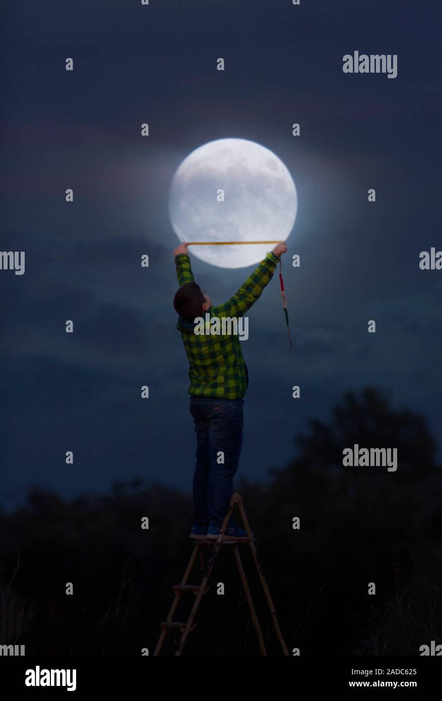 Measuring a supermoon. Child on a stepladder measuring the size of a ...