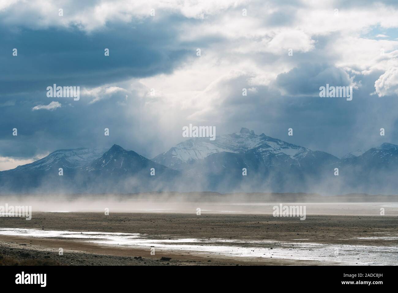 Lake shoreline and mountains. Sun breaking through clouds as the wind ...