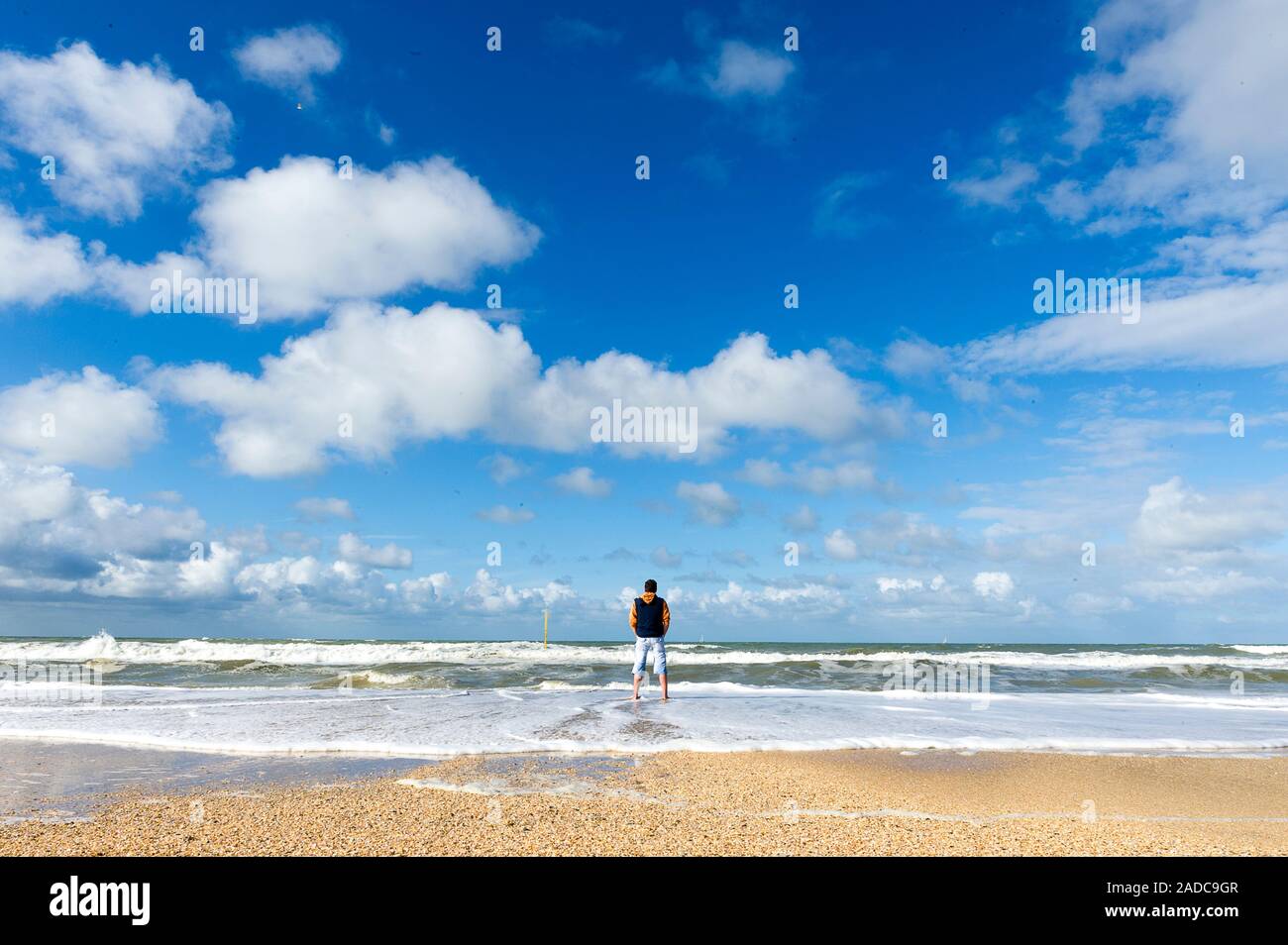 Man standing in the surf on a beach. Photographed in October, in De ...