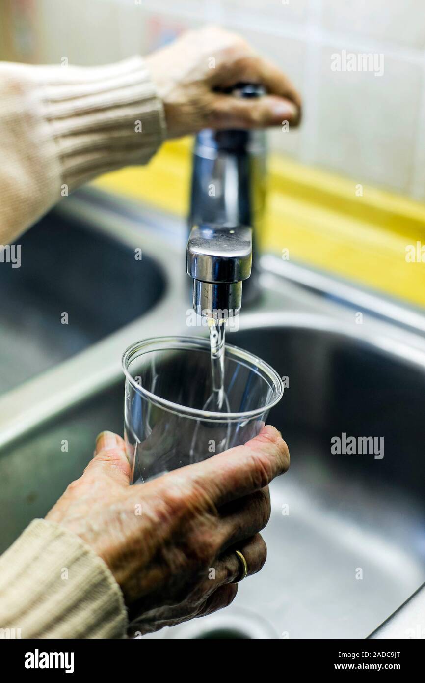 Elderly person using a tap for drinking water. Photographed during a ...