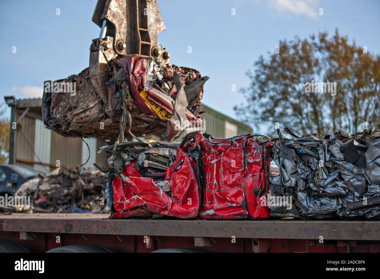 Scrapyard. Crushed cars being loaded onto a transporter at a scrapyard ...