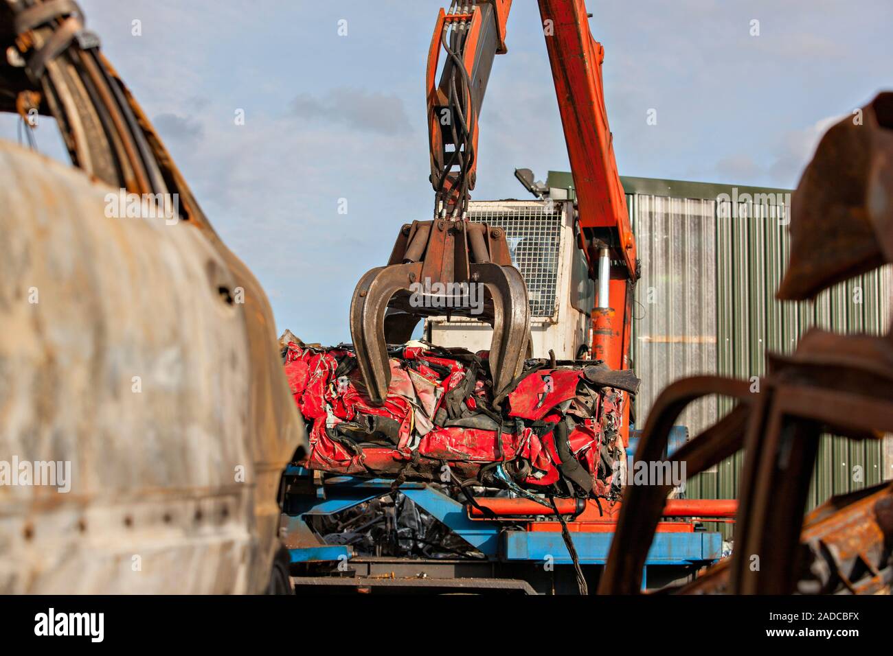 Scrapyard. Crushed cars being loaded onto a transporter at a scrapyard ...