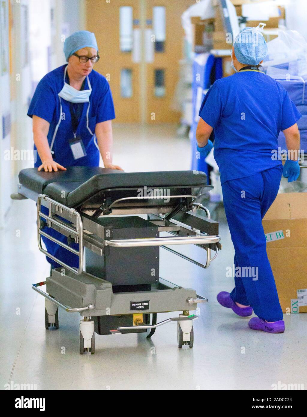 Surgical staff in a hospital corridor, with one wheeling a bed ...