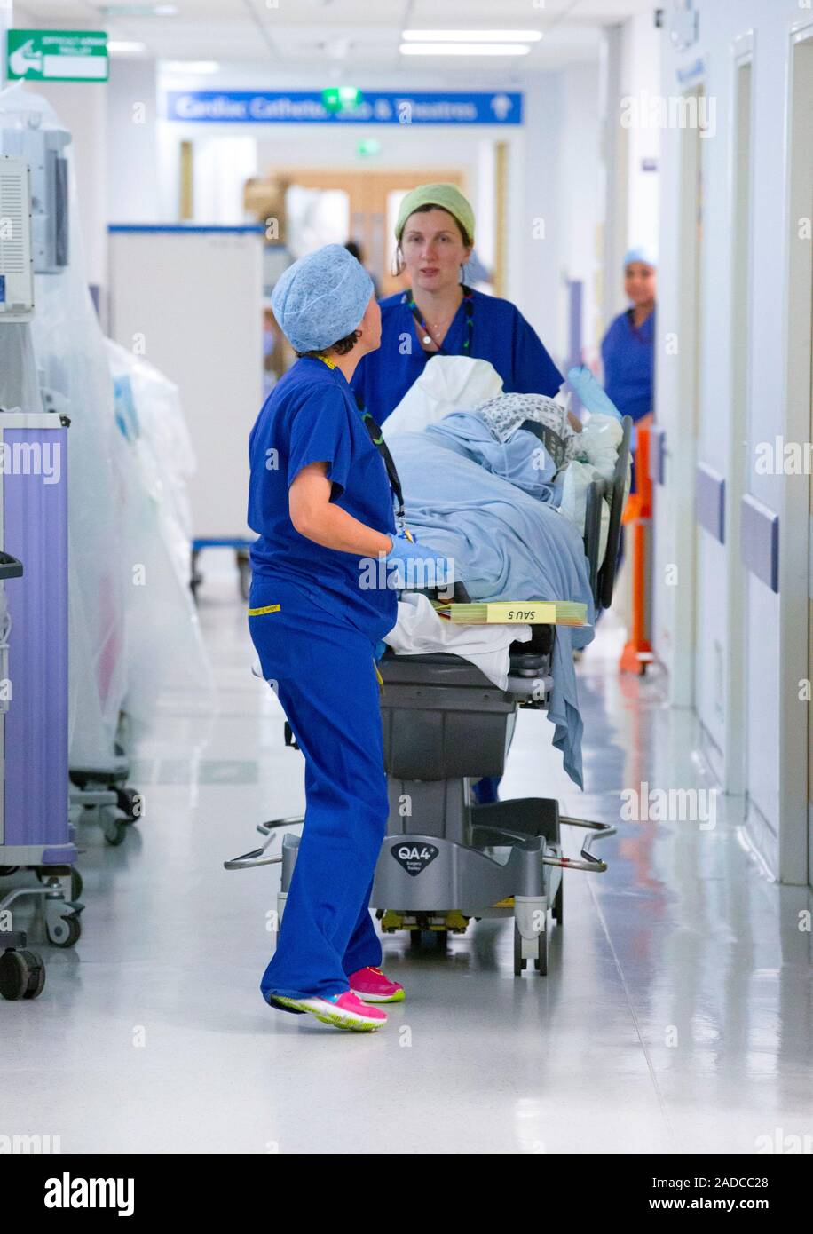 Surgical staff and patient in a hospital corridor, with the patient ...