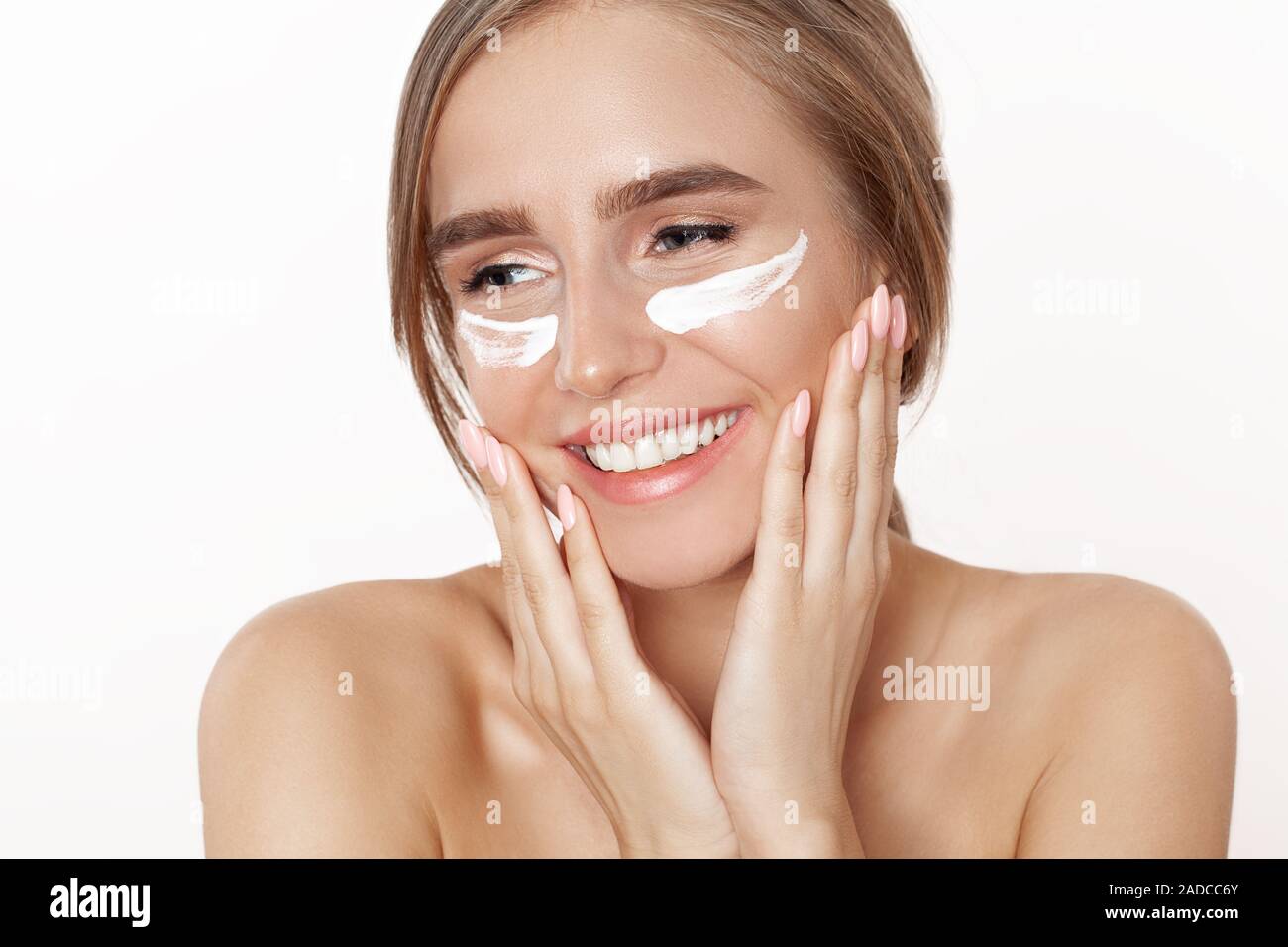 Portrait of beautiful women with perfect skin applying cream on the ...